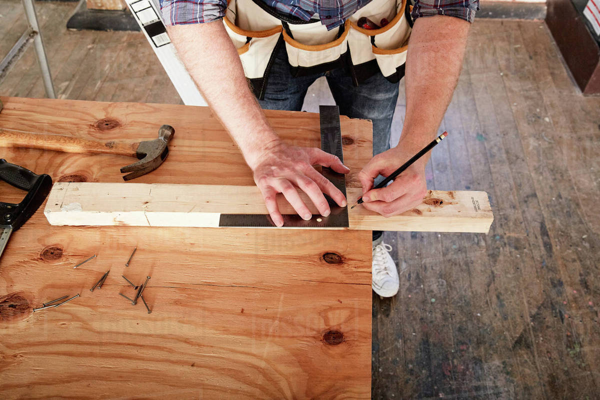 Cropped view of carpenter marking timber using set square - Royalty ...