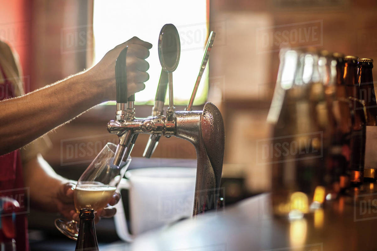 Hands of bartender pulling beer pump - Stock Photo - Dissolve