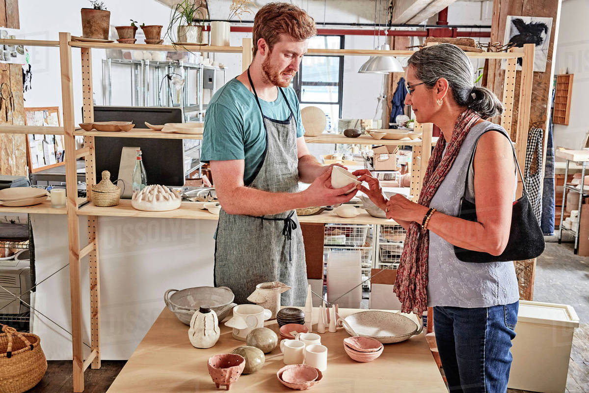 Potter in workshop showing customer pottery - Royalty-free Stock Photo ...
