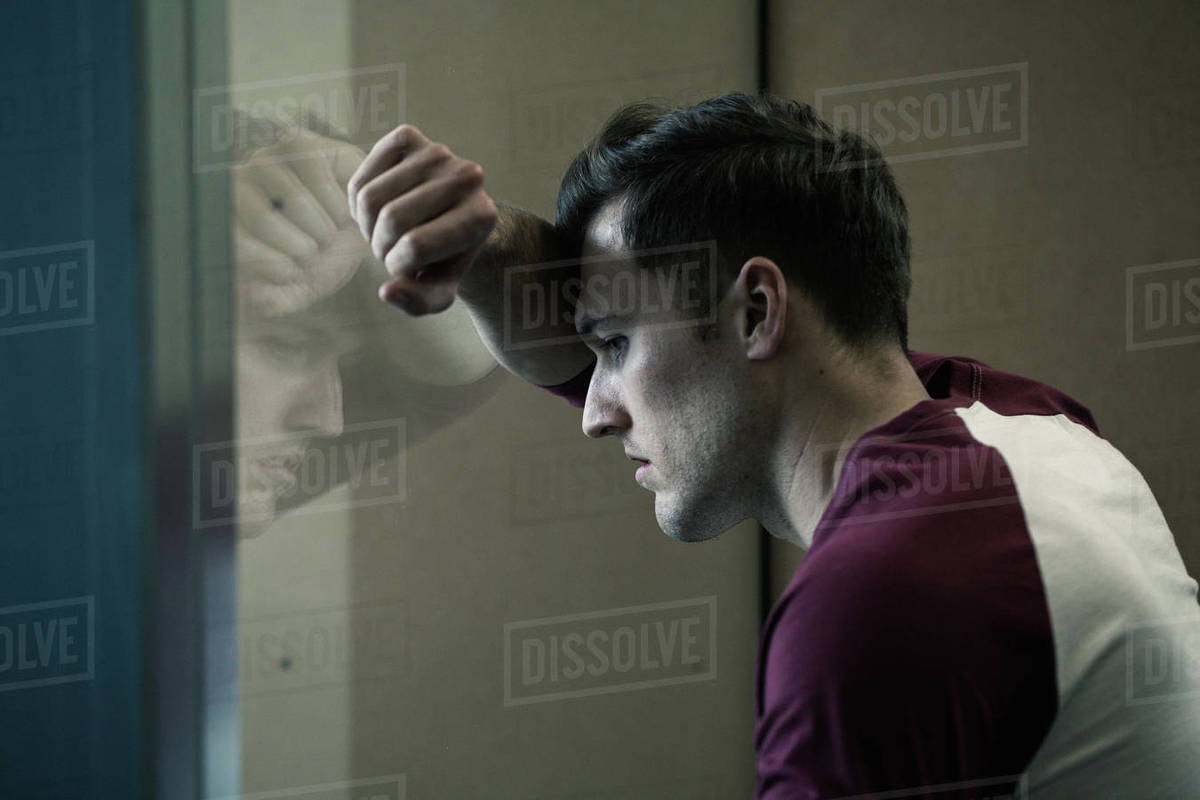 Man leaning against window looking out - Stock Photo - Dissolve