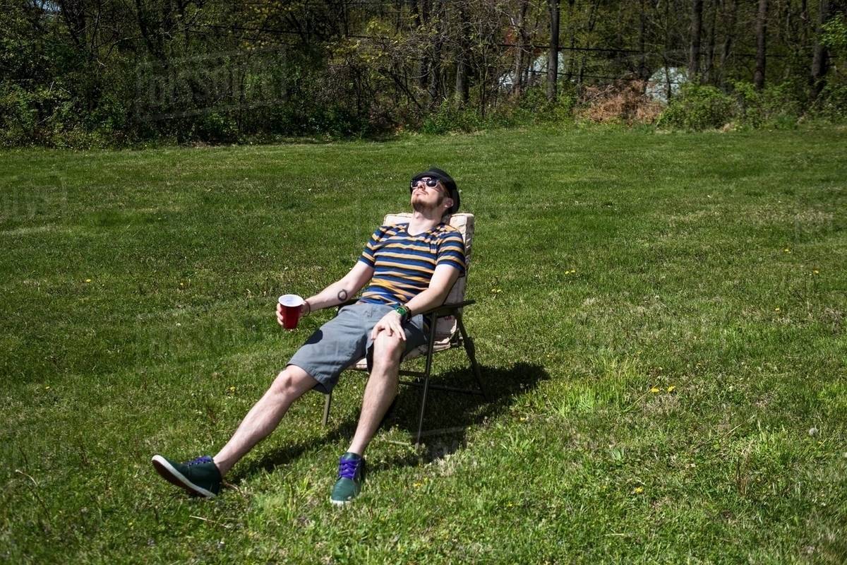 Man sitting on chair sunbathing - Royalty-free Stock Photo | Dissolve