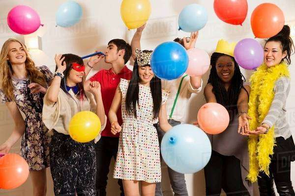 Friends at a party with balloons, studio shot - Stock Photo - Dissolve