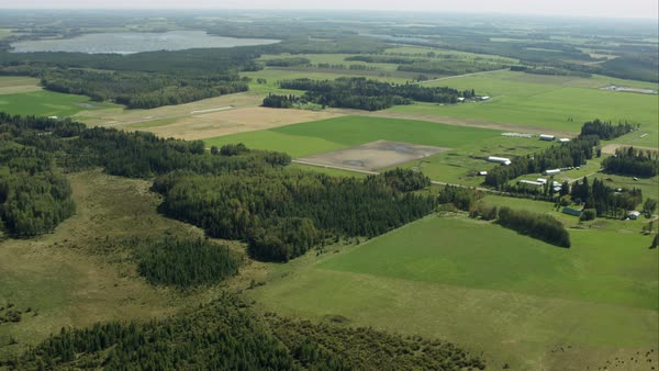 An aerial view of farmland and forests with a large body of water in ...
