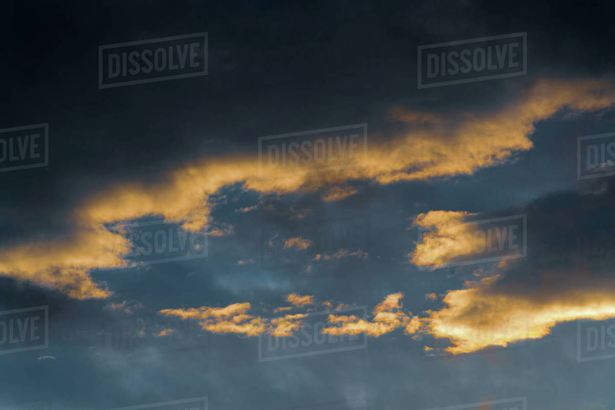 Thunderstorm clouds illuminated by disappearing rays at sunset and dark ...