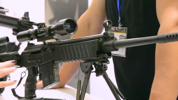 Weapon optics sight of sniper rifle with man close-up in store or shop ...