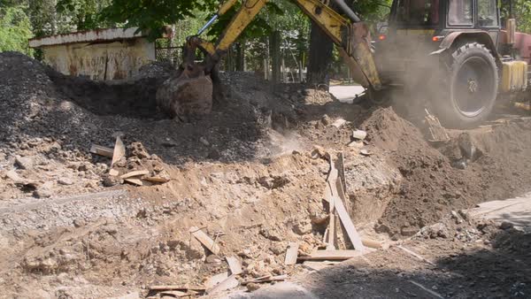 Tractor pits the ground. Backhoe piles up the ground close-up. Old ...