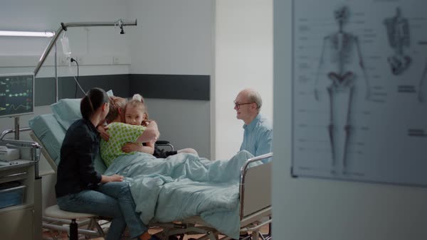Child hugging sick patient in hospital ward bed at family visit with ...
