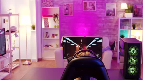 Over shoulder view of girl playing online shooter games sitting on ...