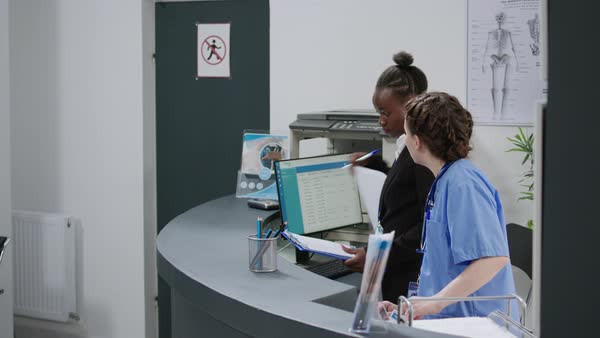 Diverse medical team working at hospital registration counter in lobby ...