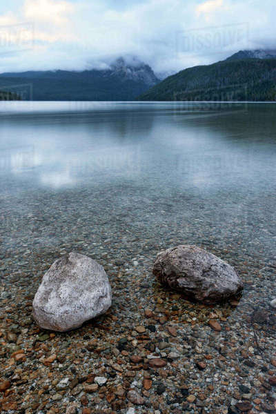 Two boulders in the shallow Redfish Lake with the Sawtooth Mountains of ...