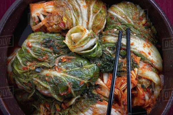 A studio overview of whole kimchi freshly made stacked inside a large ...