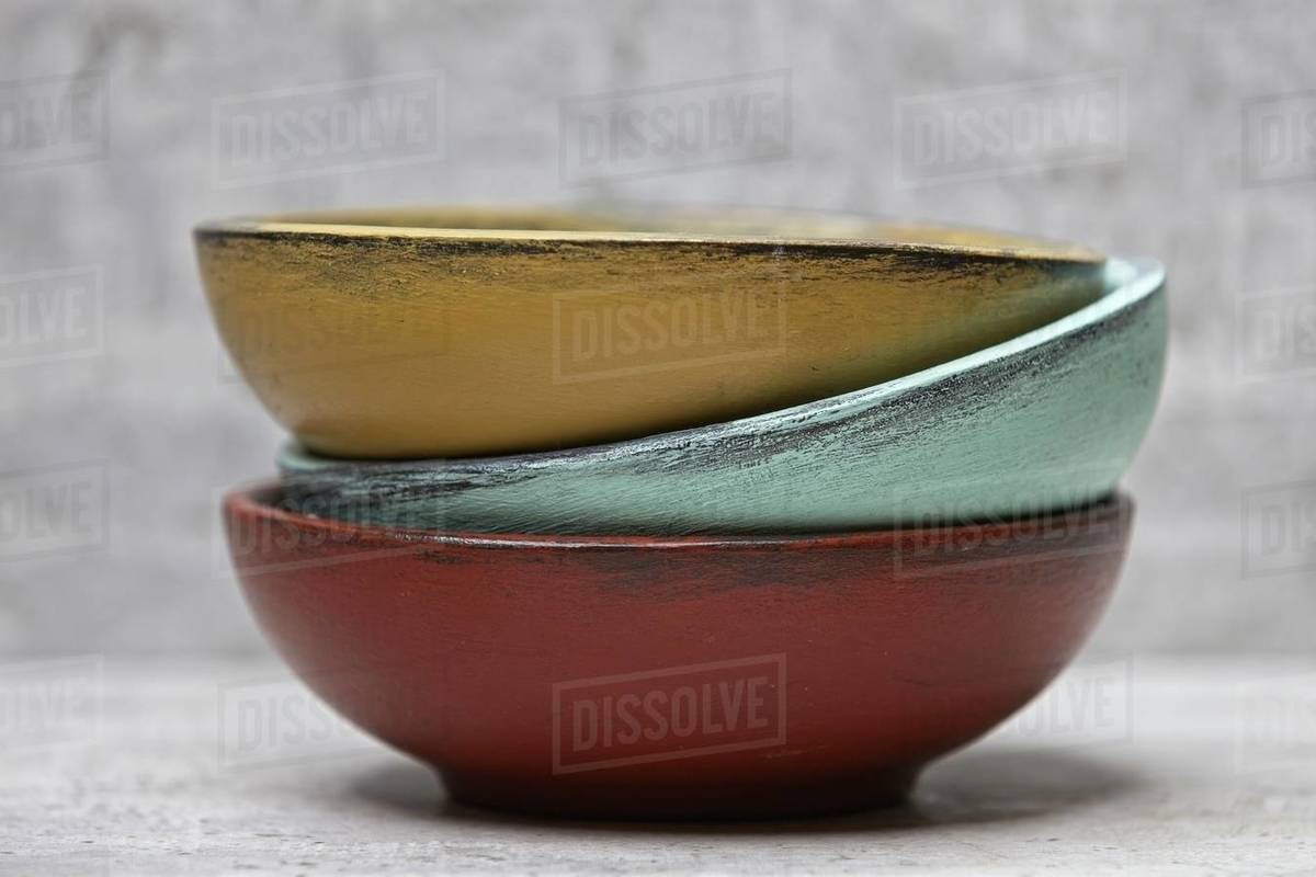 A close up studio photo of three different colored wooden bowls stacked ...