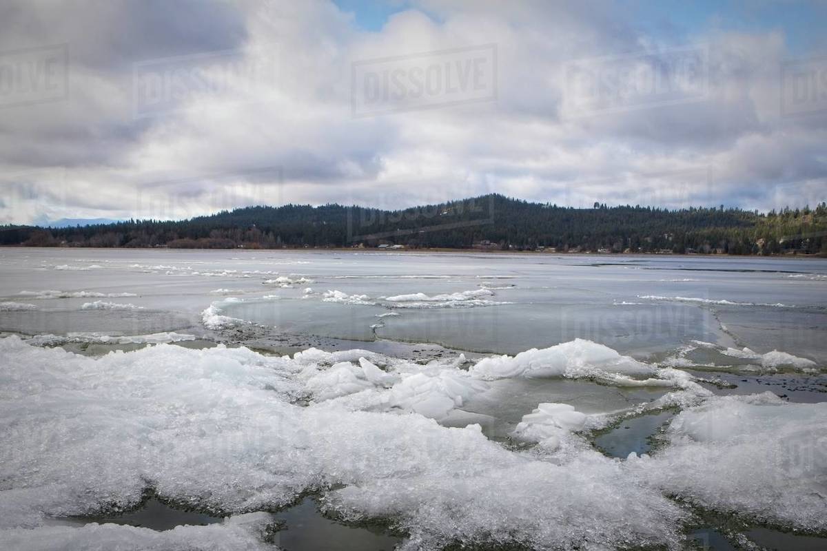 Snow is layered in clumps on a frozen yet slowly melting Hauser Lake in ...
