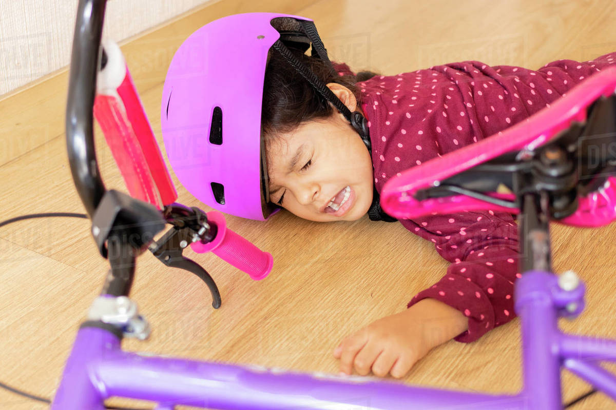 Sad little girl fell to the ground while playing with her bicycle in ...