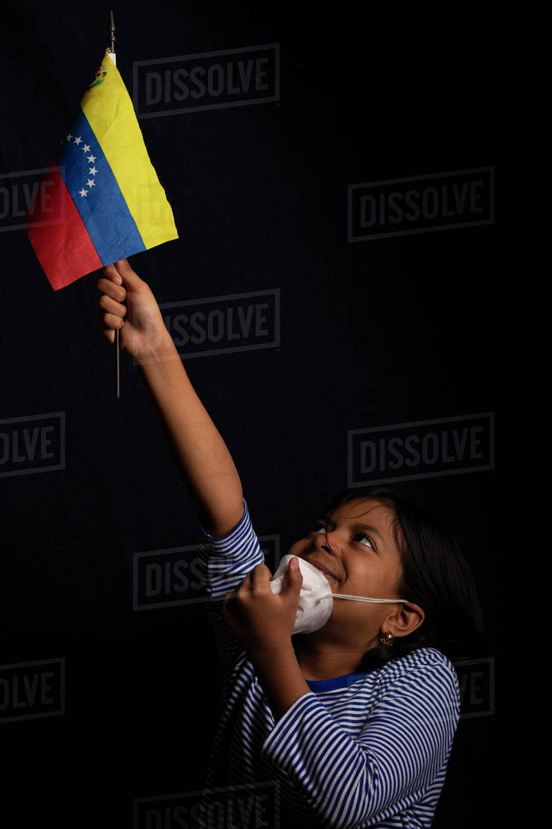 Portrait of little Venezuelan girl wearing medical mask and holding ...