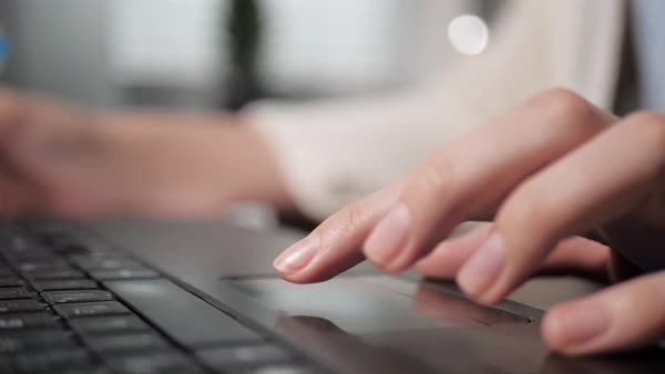 Left female hand moves finger across laptop touchpad and presses right ...