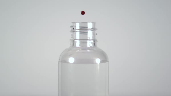 Drop of red liquid falling in clear vial in slow motion filmed with ...