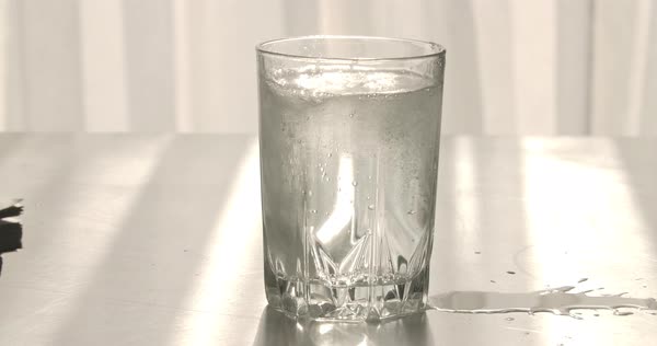 Dropping of soluble pill into glass of transparent water. Medication ...
