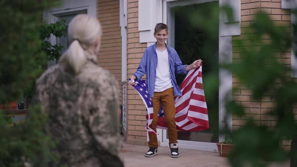 Wide shot joyful teenage boy dancing with American flag in slow motion ...