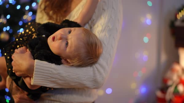 Portrait of happy calm baby girl lying on female hands as woman shaking ...