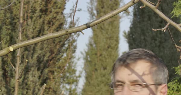 Side view of adult Caucasian man cutting dry branch of tree and leaving ...