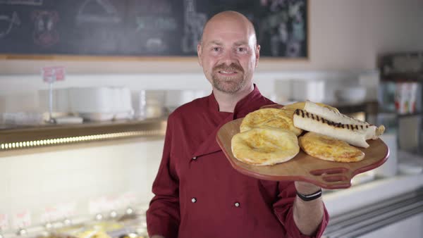 Bearded male Caucasian cook posing with tray with cooked tasty pinza ...