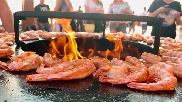 Close up footage of process of grilling fresh king prawns on brazier ...