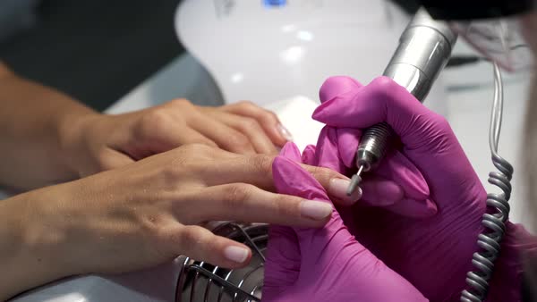 Closeup of manicurist removes gel shellac polish from client's nails ...