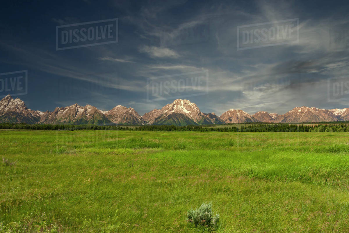 Photograph of a large mountain range in the distance with snow caps on ...