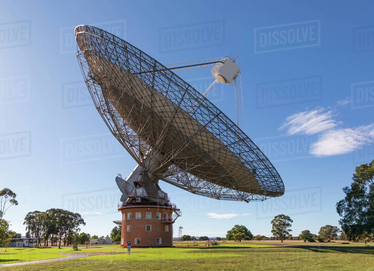 A large outdoor scientific radio telescope in the sunshine in a green ...