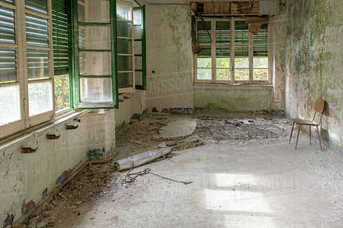 Old abandoned building room in the wood with windows and a chair ...