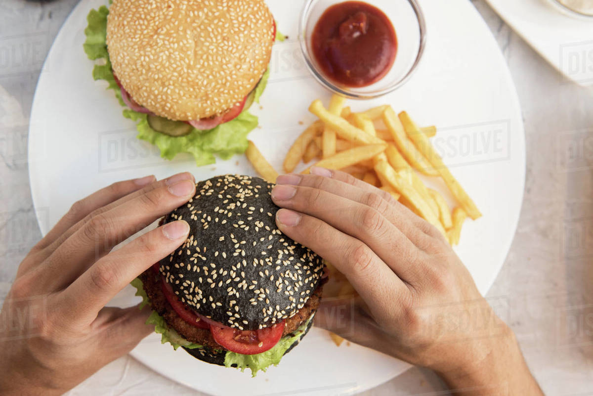 Man eating burgers at table, closeup photo - Royalty-free Stock Photo ...