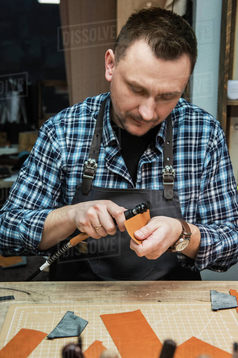 Man working with leather textile at a workshop. Craftman cutting ...