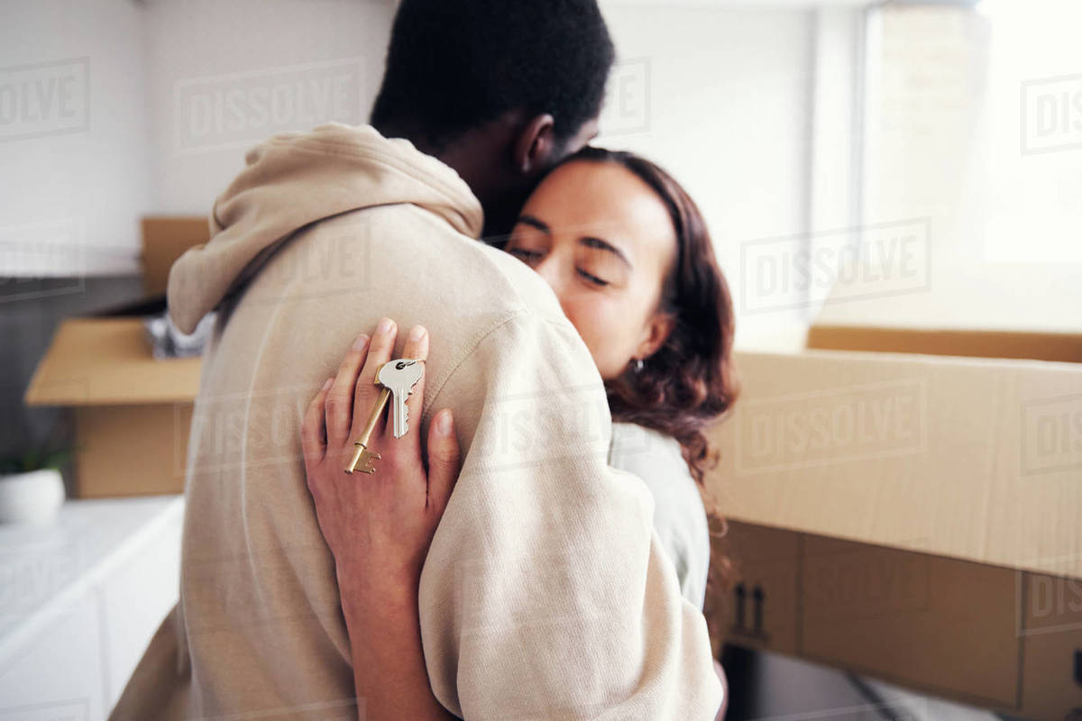 Close up of young couple holding keys to new home standing in kitchen ...
