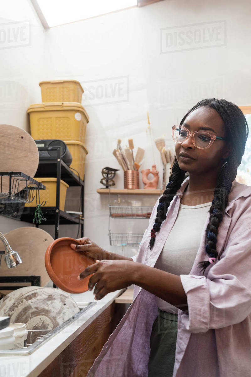 Woman washing her pottery at the ceramics studio - Stock Photo - Dissolve