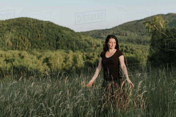 A portrait of a woman walking on her own through tall grass. A woman ...