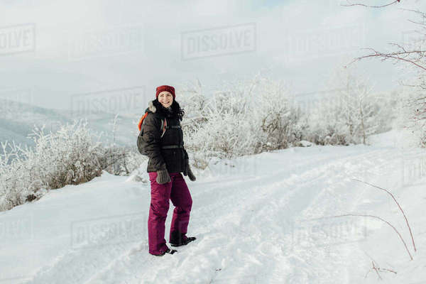 Happy female tourist standing on a snow trek and looking back - Royalty ...