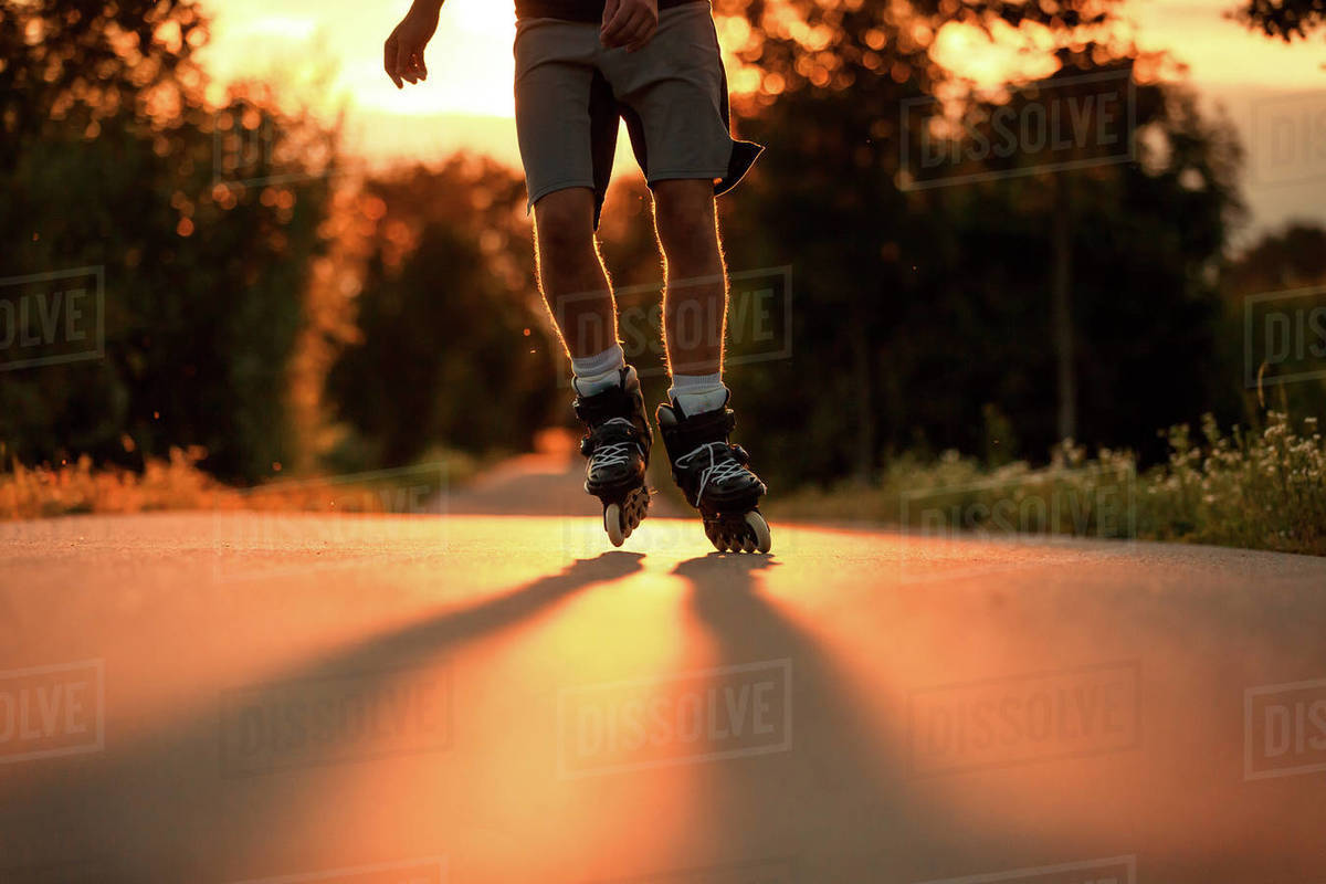 Young man on the roller skates during lovely summer sunset, sport ...