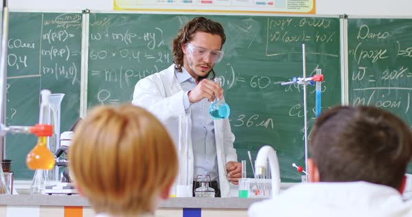 Lesson of chemistry at school. Caucasian male teacher in goggles ...