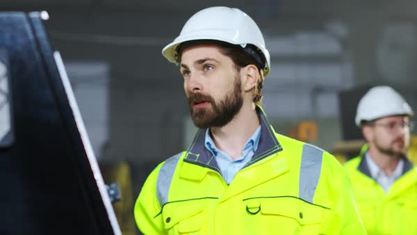 Close up of Caucasian male worker of plant in helmet and yellow uniform ...