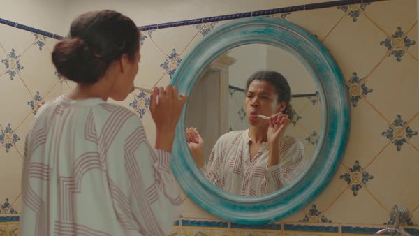 Very positive 20s African American woman brushing her teeth and dancing ...