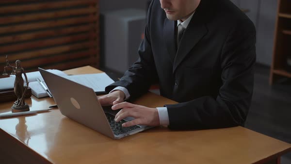 Young male boss typing on laptop keyboard and sitting at table in ...