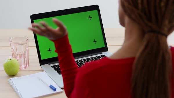 Black girl watching green screen of laptop at desk. Chroma key video ...