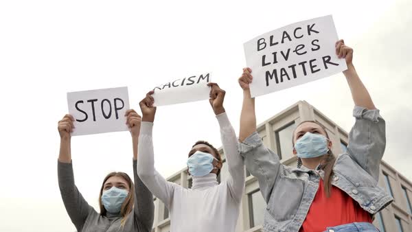 Three young people in a medical masks protest against racial inequality ...