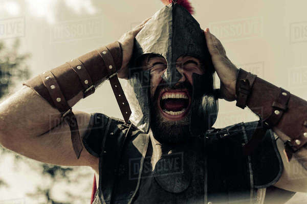 Portrait of screaming in rage ancient Spartan warrior in battle dress ...