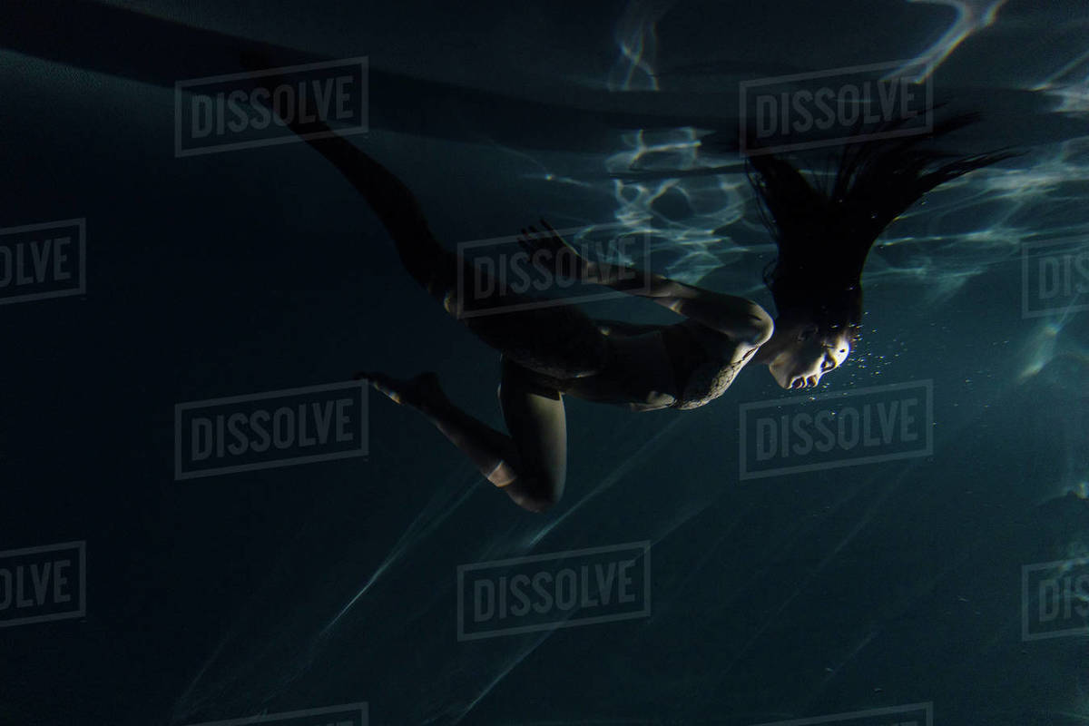 Underwater shoot of beautiful woman with long hair dancing in water in ...