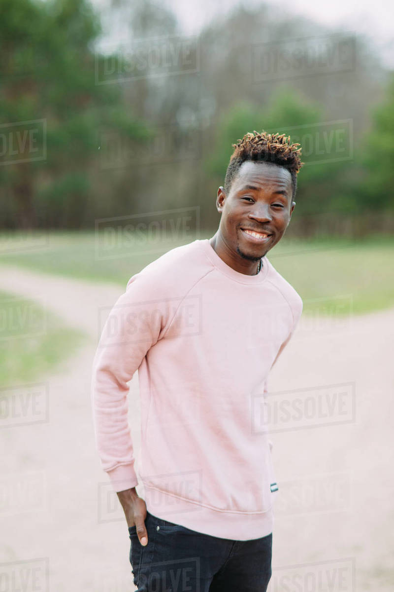 Happy African man stands and smiles. - Stock Photo - Dissolve