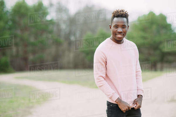 Happy African man stands and smiles. - Stock Photo - Dissolve