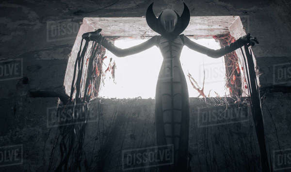 Woman in the image of the alien creature stands inside old abandoned ...
