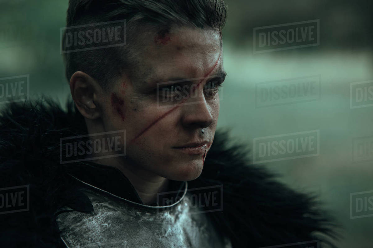 Portrait of medieval warrior knight in armour with bloody face and scar ...